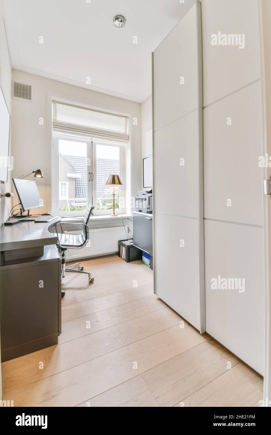 Delightful small work room with large window and wardrobe Stock Photo ...