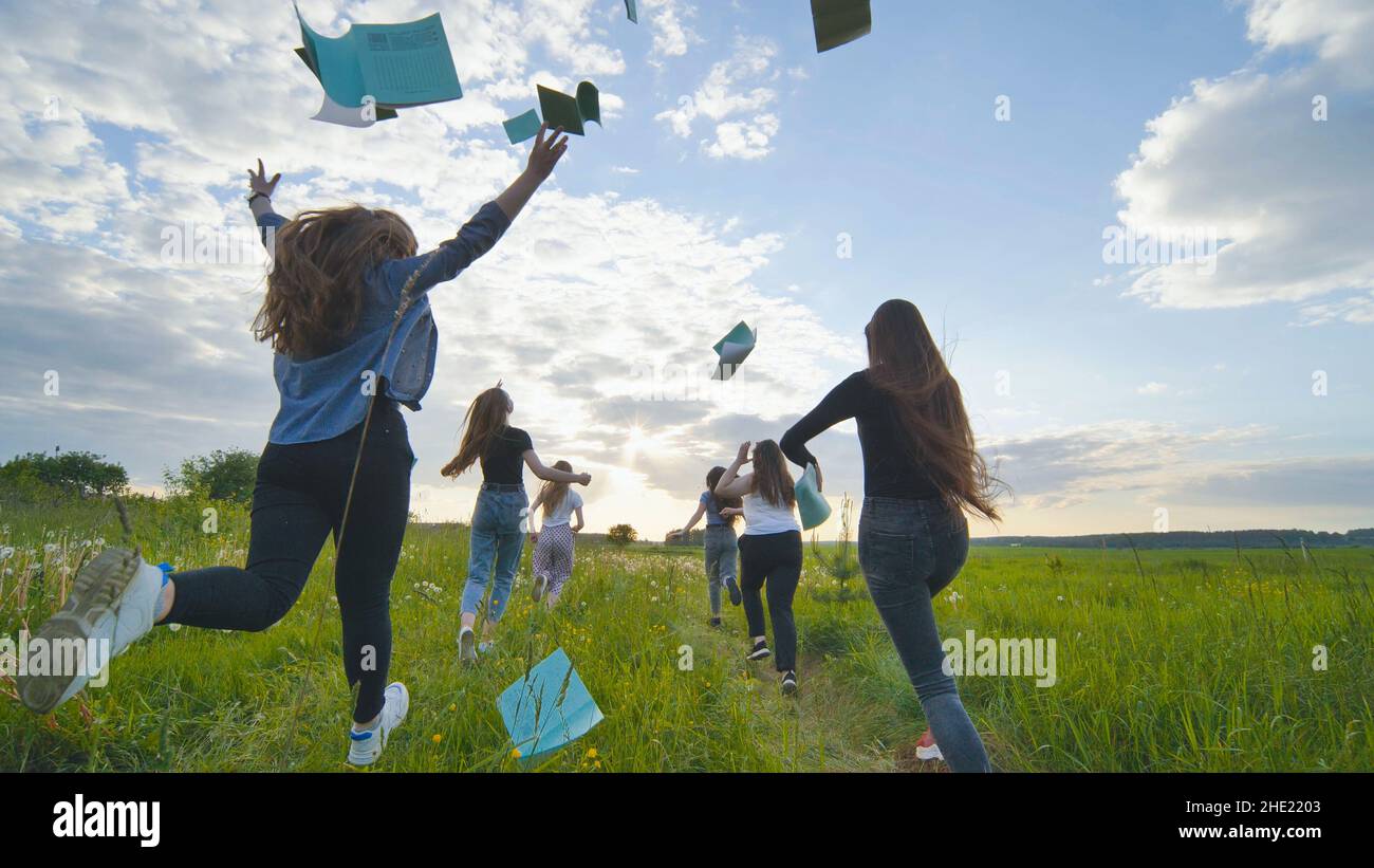 Cheerful students run throwing notebooks after school at sunset Stock ...