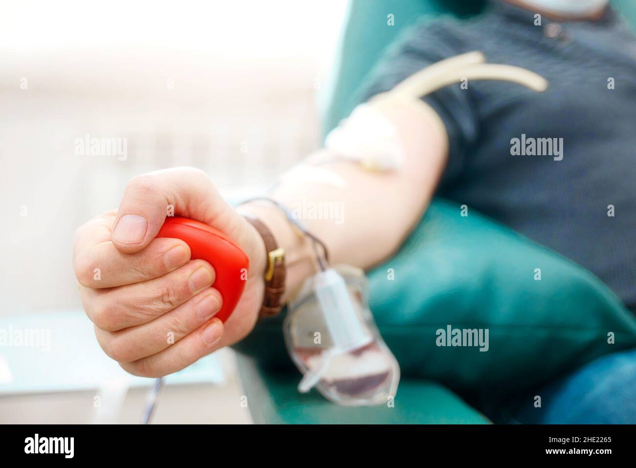 Topic of donation. Man donates blood in hospital. Man's hand squeezes ...