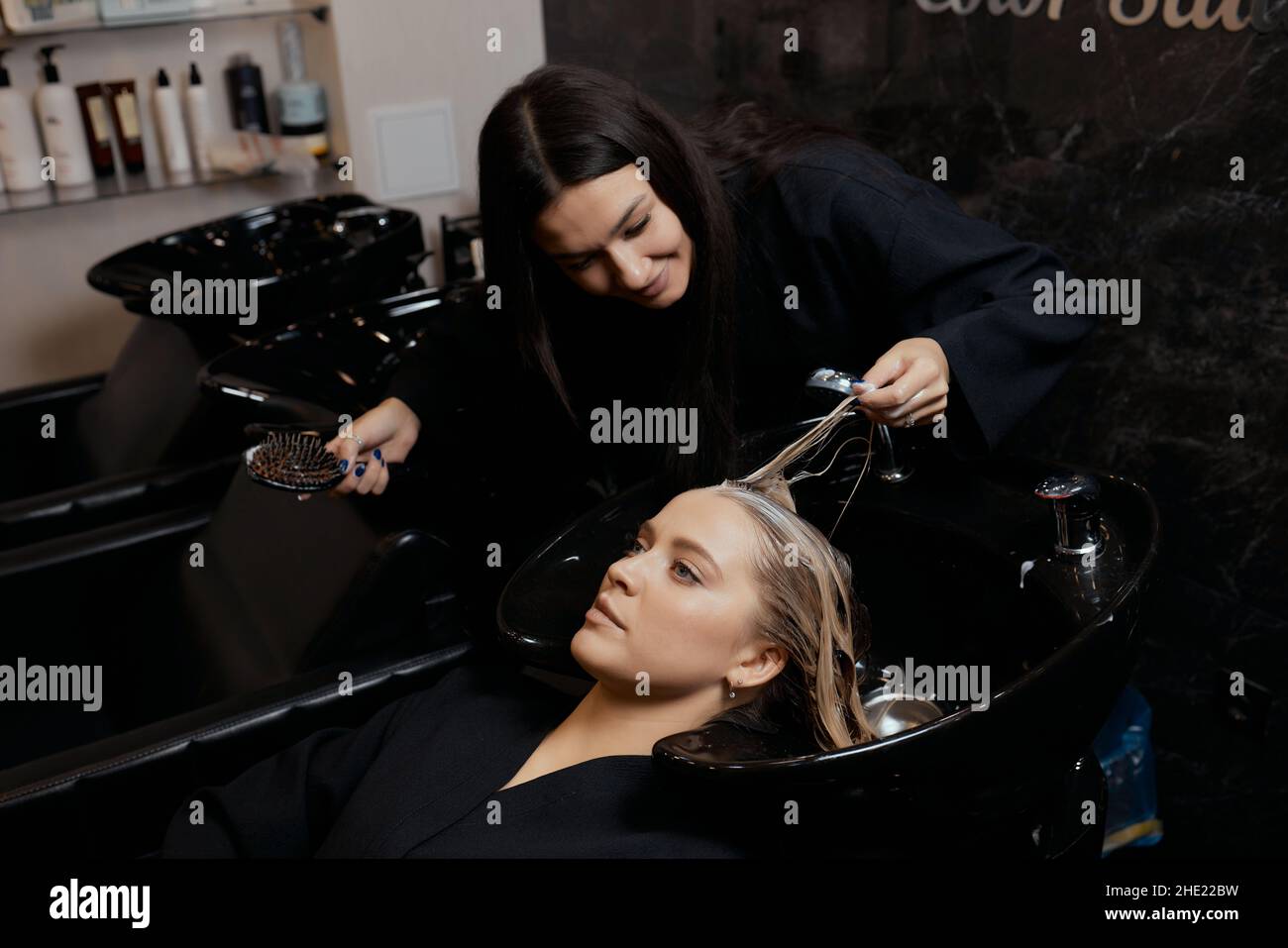 Hairdresser in beauty salon washes his client hair, before procedure of ...