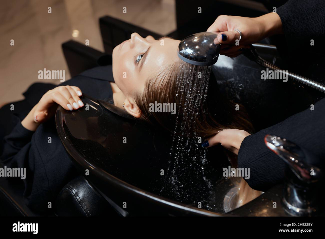 Hairdresser in beauty salon washes his client hair, before procedure of ...