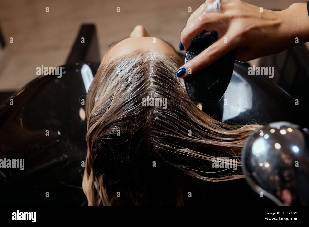 Hairdresser in beauty salon washes his client hair, before procedure of ...