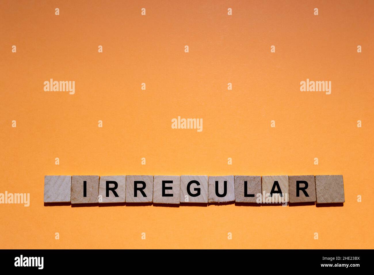 IRREGULAR. Word written on square wooden tiles with an orange ...