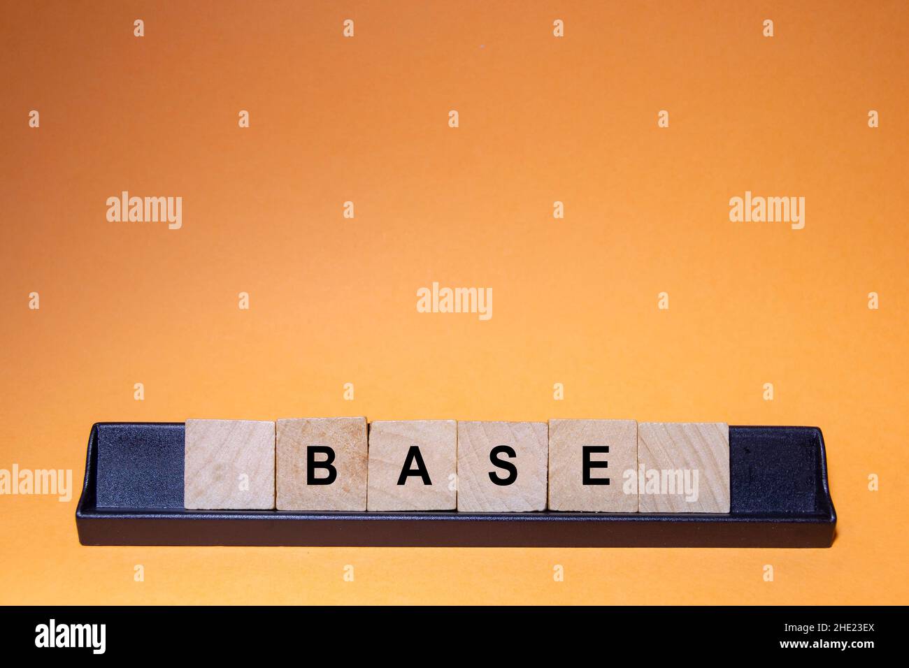 BASE. Word written on square wooden tiles with an orange background ...