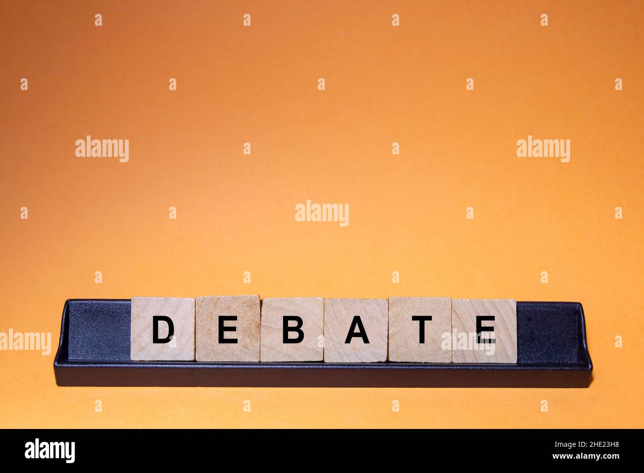 DEBATE. Word written on square wooden tiles with an orange background ...