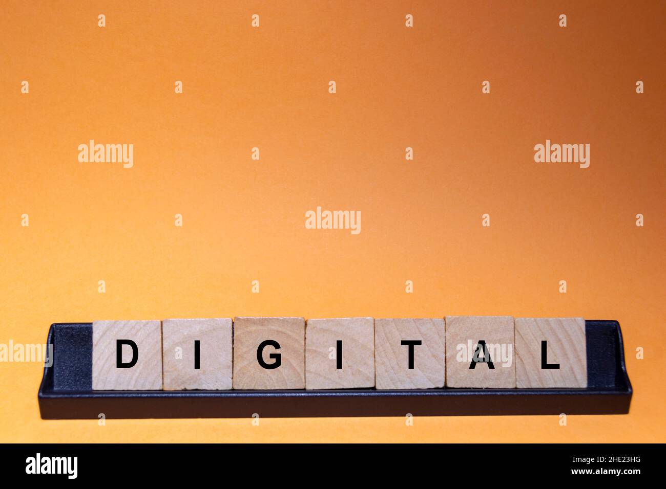 DIGITAL. Word written on square wooden tiles with an orange background ...