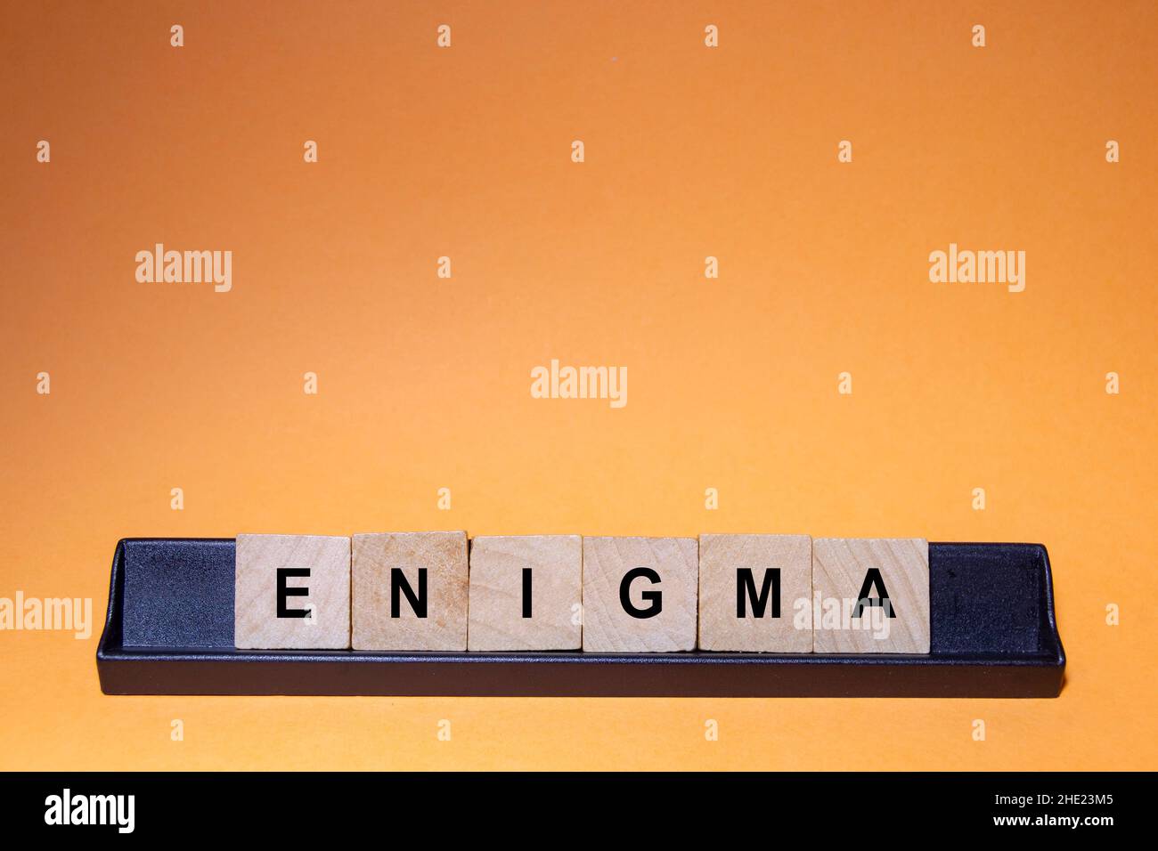 ENIGMA. Word written on square wooden tiles with an orange background ...