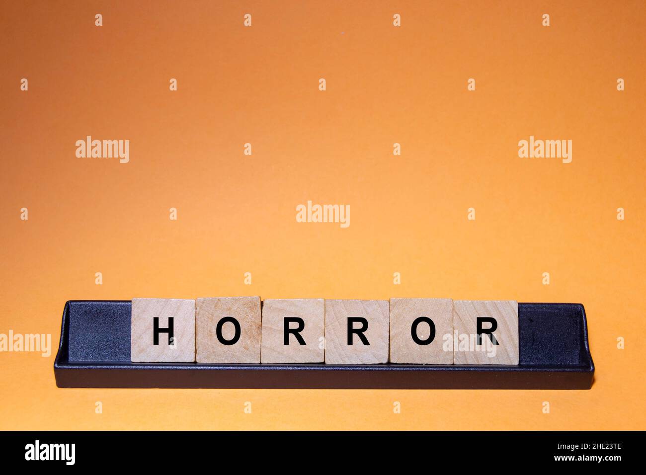 HORROR. Word written on square wooden tiles with an orange background ...