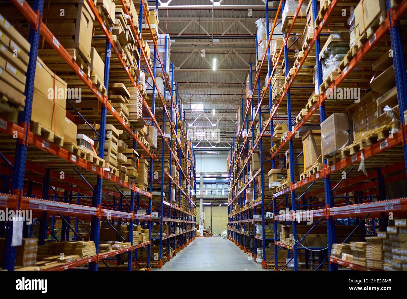 Huge distribution warehouse with high shelves and loaders Stock Photo ...