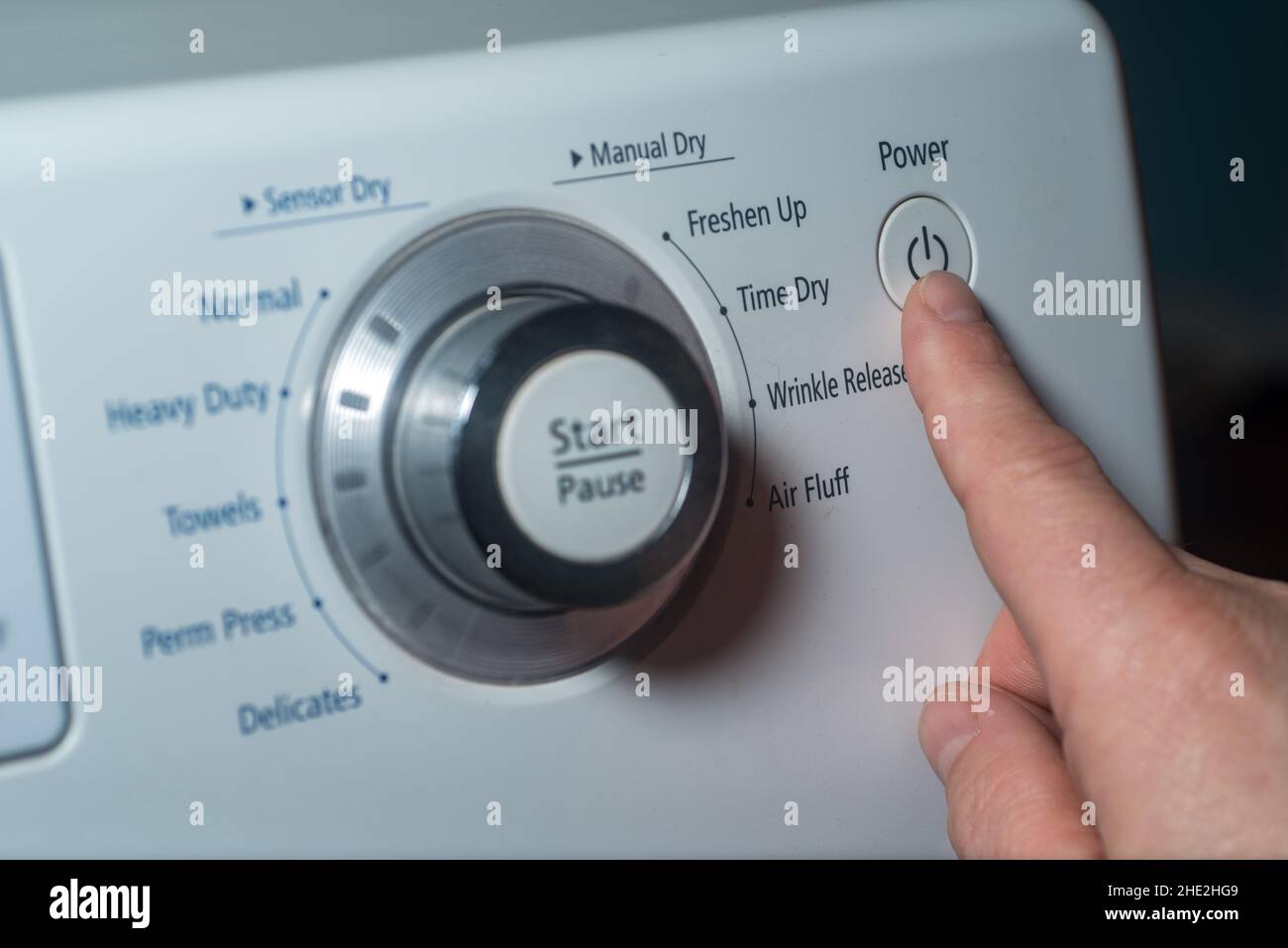 Finger pushing power button on electric dryer Stock Photo - Alamy