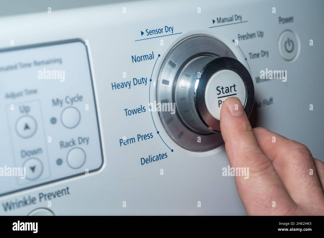 Finger pushing start button on electric dryer Stock Photo - Alamy