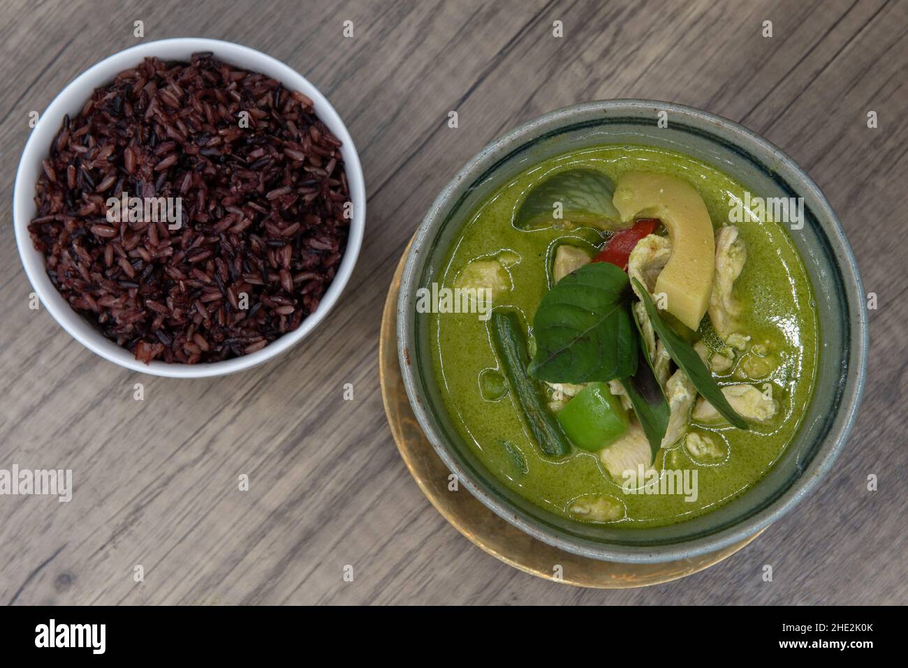Overhead view of spicy bowl of green curry with chicken served with a ...