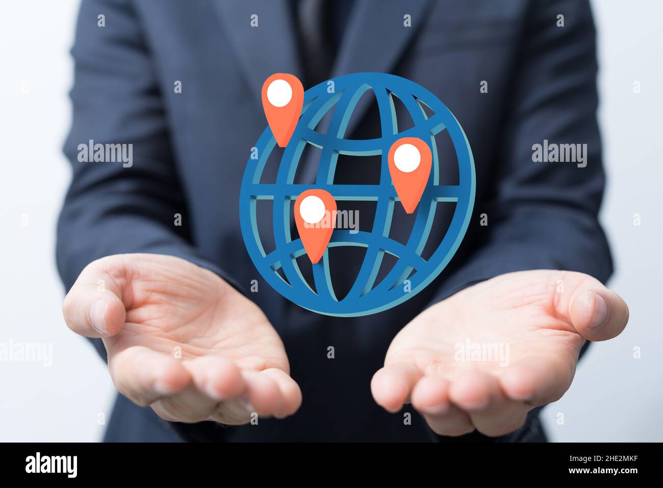 Businessman holding a floating render of a globe with marked locations ...