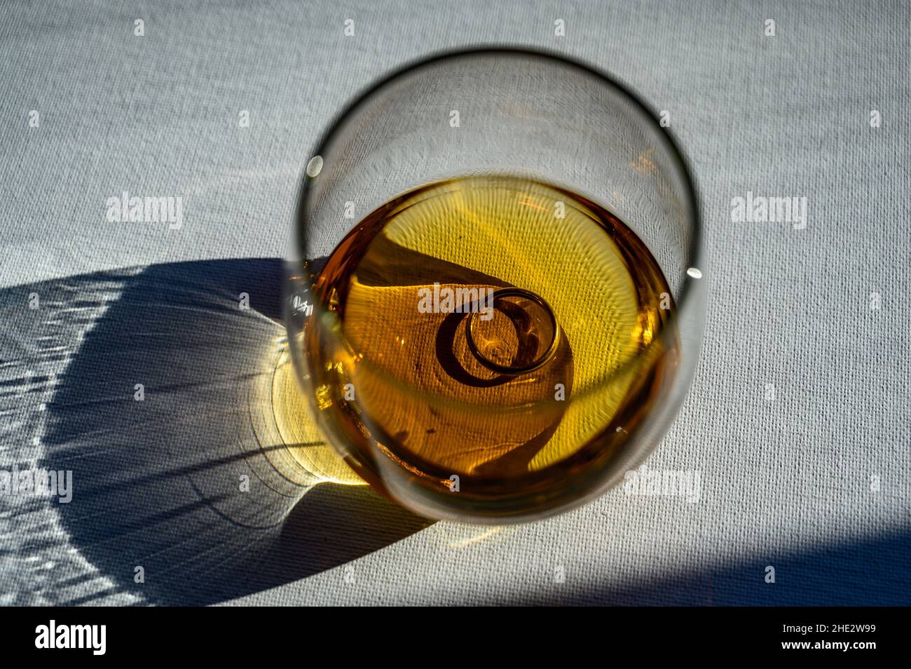 light refracting through a glass of amber colored liquid with a wedding ...