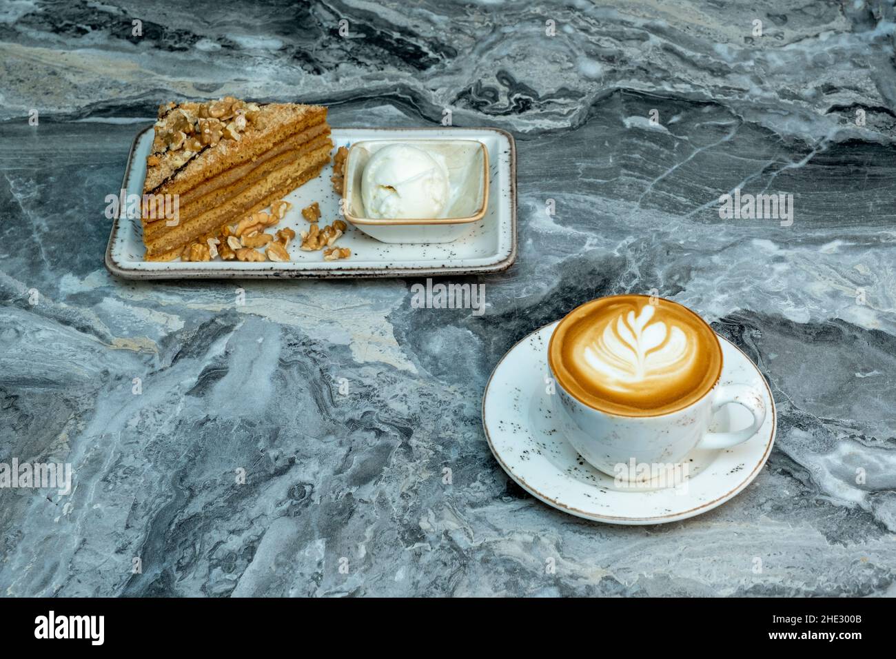 Cup of cappuccino and slice of cake with latte art on marble background ...