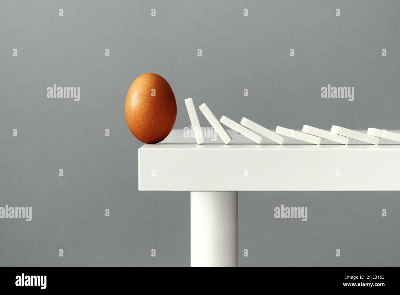 Egg balancing on the edge of a table, about to fall down and break due ...