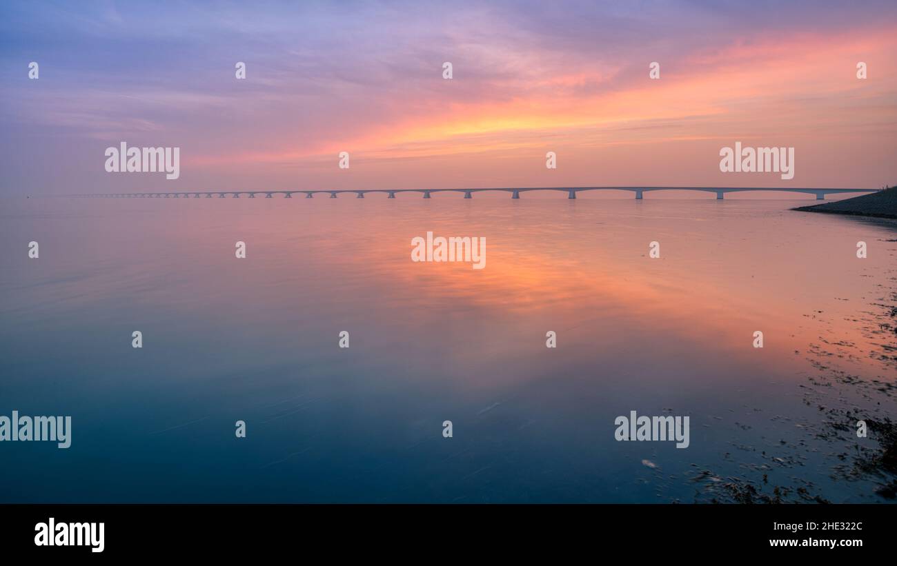 Long bridge over glassy smooth water going to infinity over the ...
