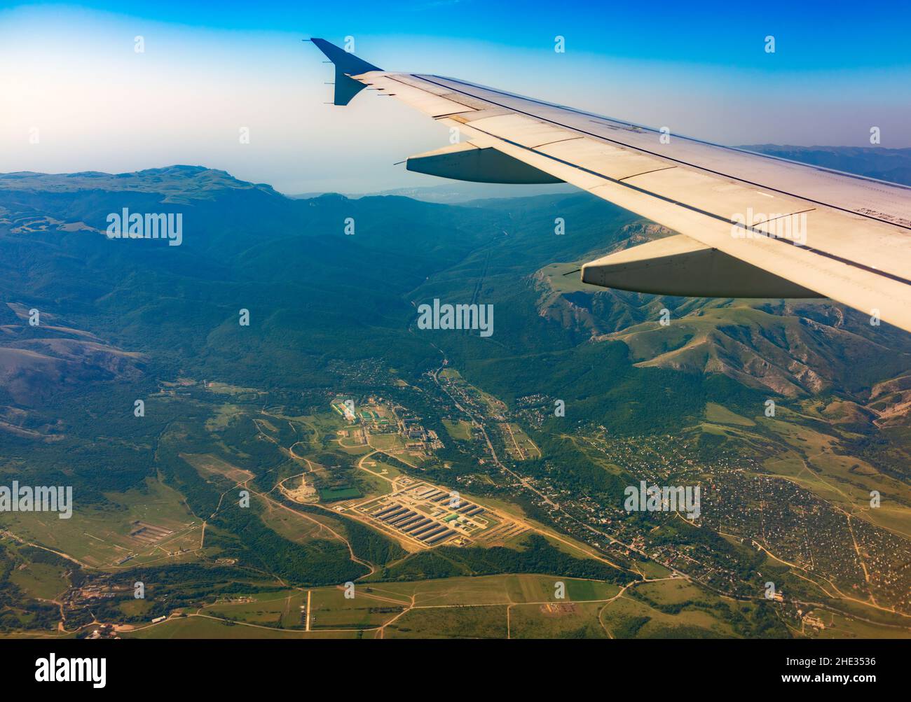 View of airplane wing, blue skies and green land during landing ...