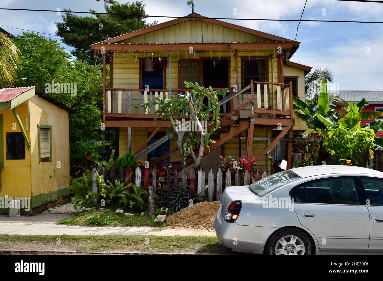 A yellow wooden house with brown trim and a cactus garden in a Belize ...
