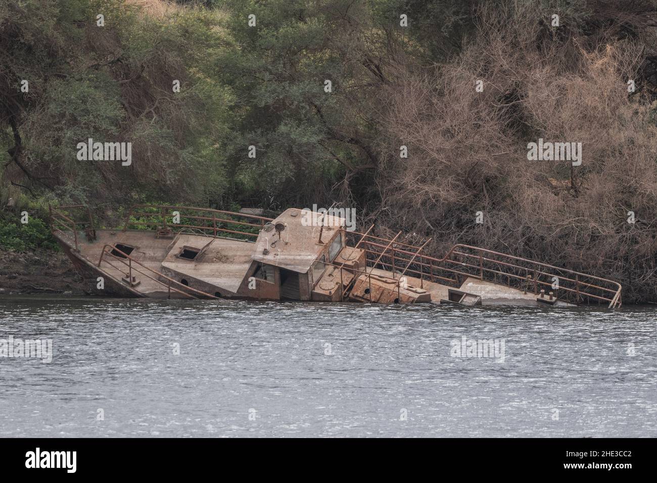 A sunken wreck of an old boat on the edge of the Nile river in Egypt ...
