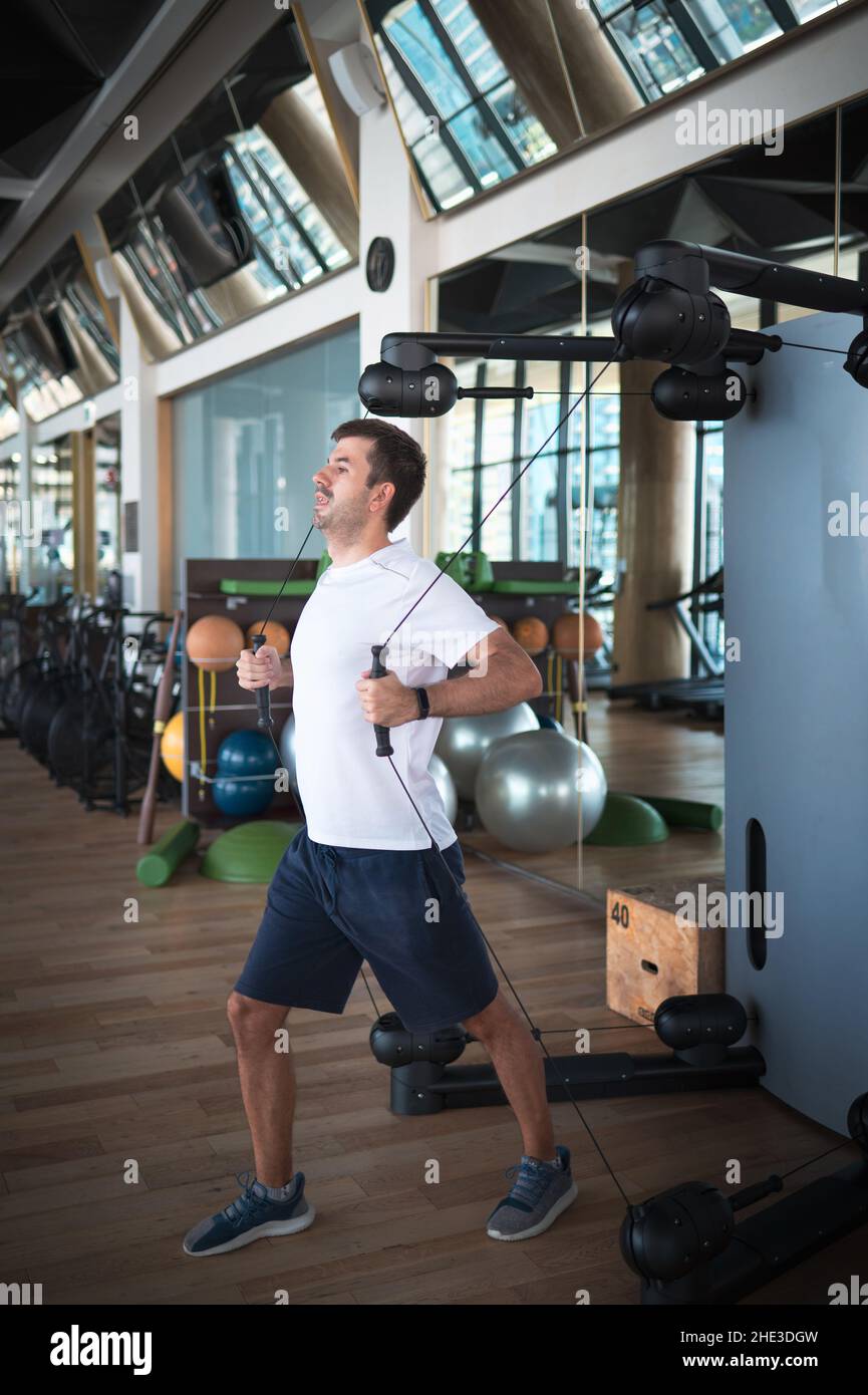 Man exercising in the gym on a pec deck machine for chest and pectoral ...