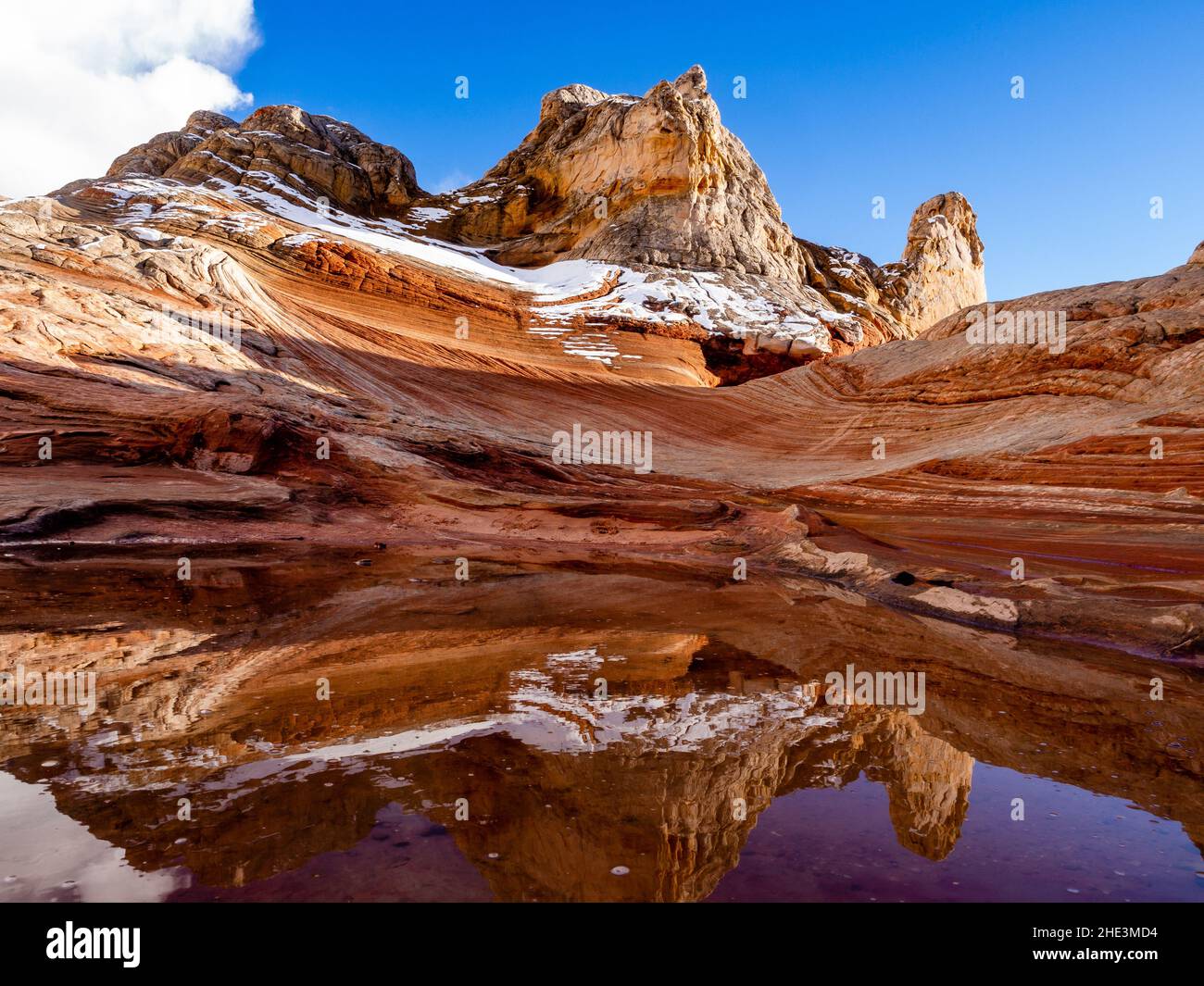 A rare occurrence, snow on red rocks reflected in water in an alcove at ...