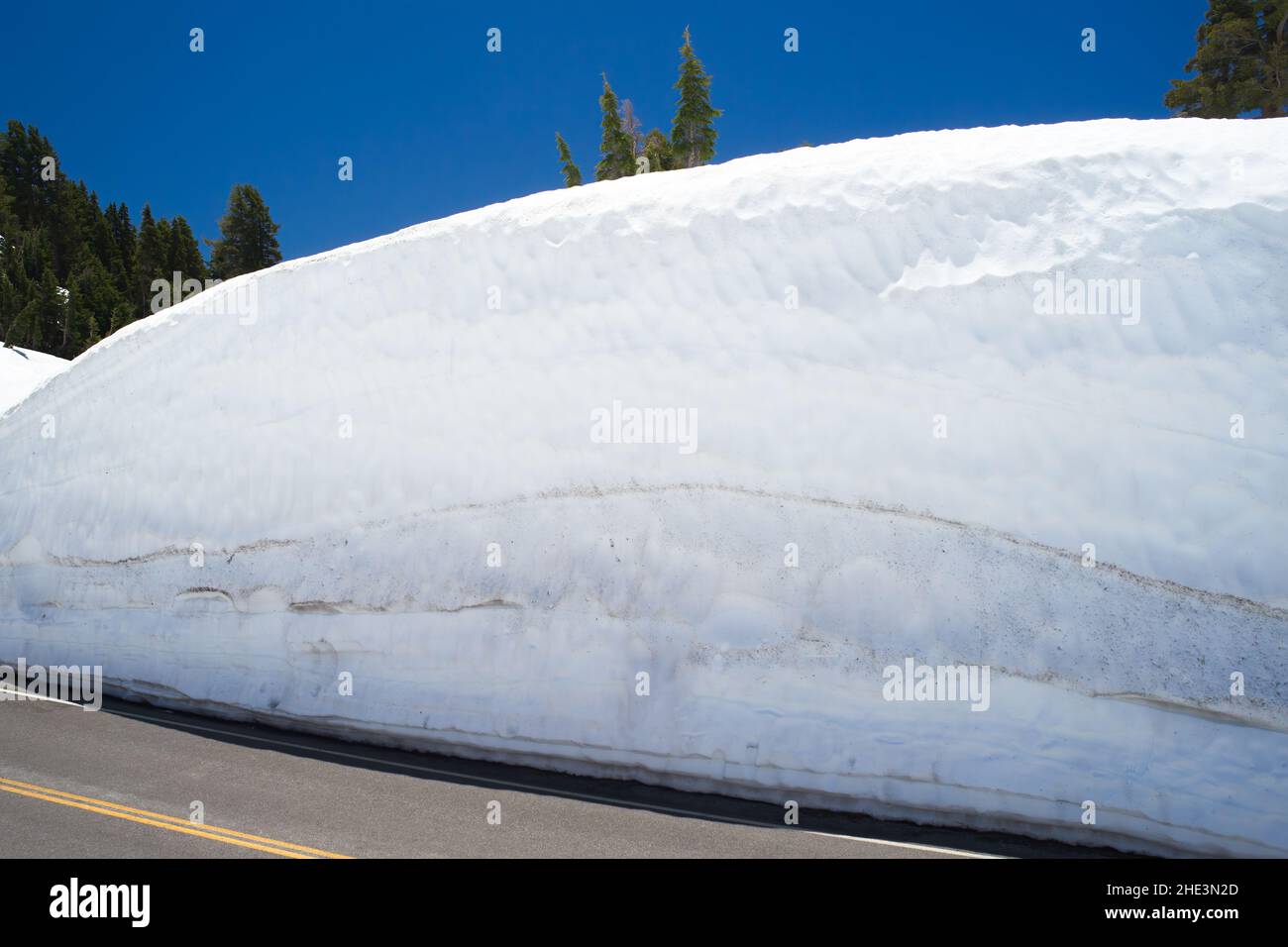 Very large snowdrift by the roadside on a blue sky day Stock Photo - Alamy