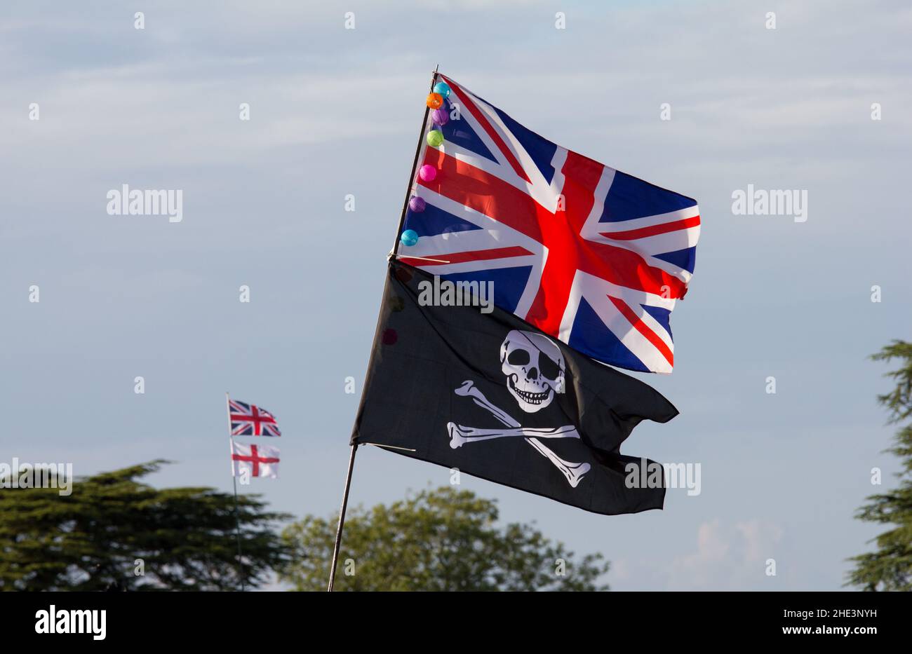 Union flag over a Jolly Roger pirate flag with flag of St George in the ...