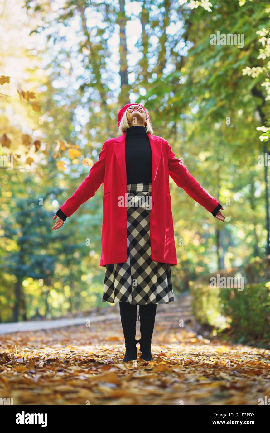 Happy woman opening her arms with her eyes closed in a park full of ...