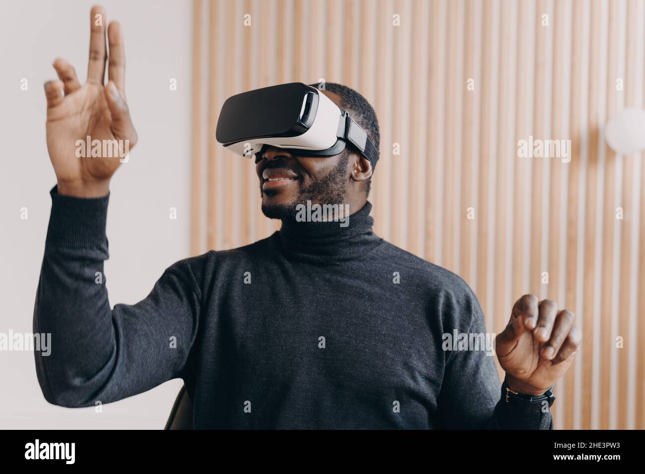 Smiling african american businessman in VR glasses sits in office ...