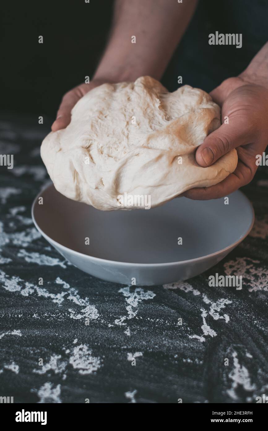 Male hand holding yeast dough in his hands on a dark background Stock ...