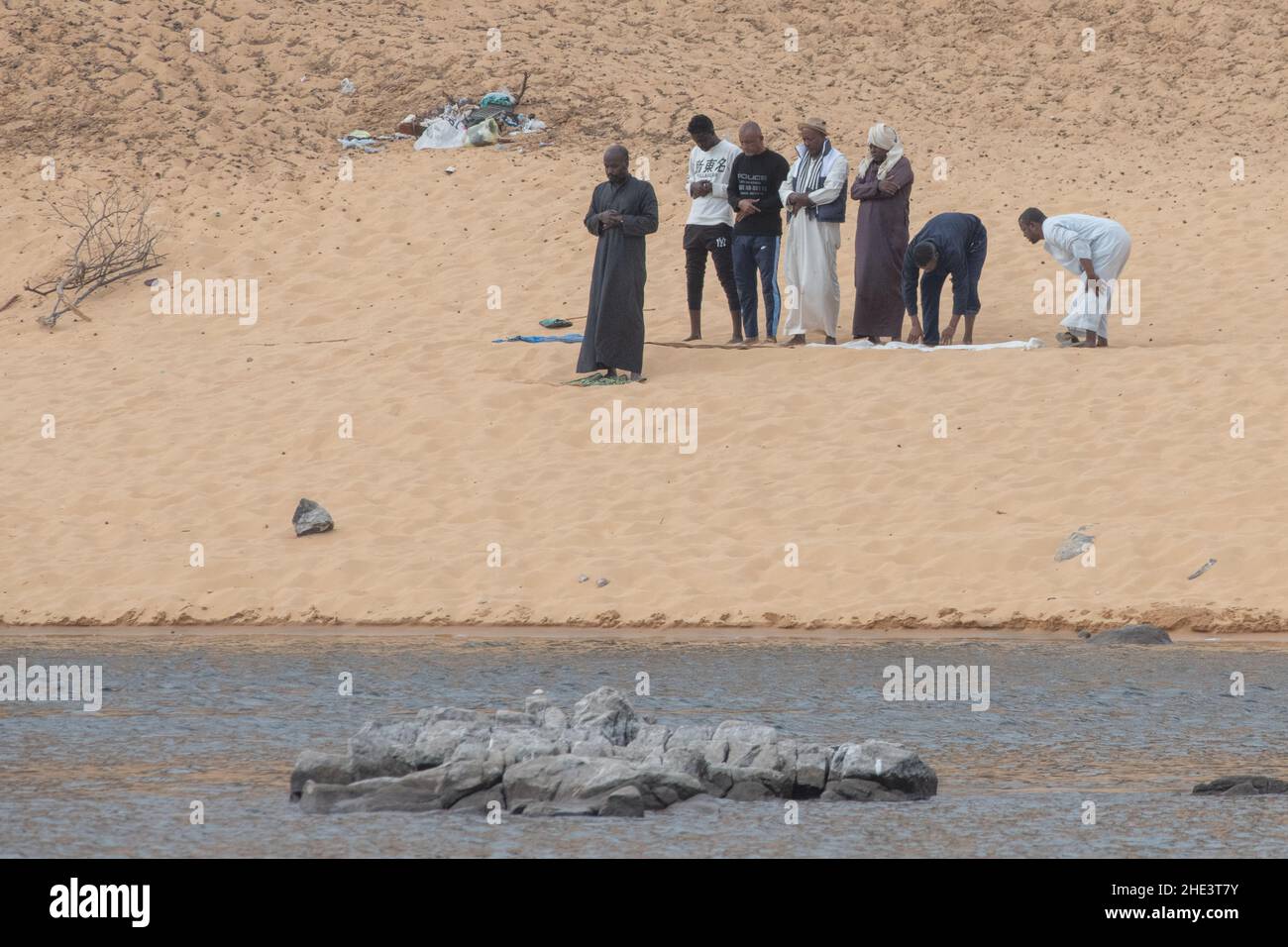A group of muslim men do their daily ritual prayer, Salat, on the banks ...
