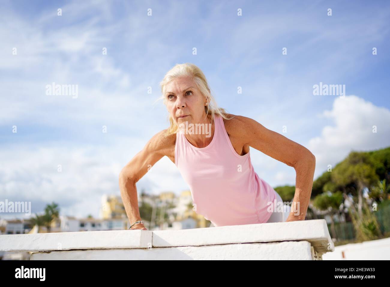 Mature woman working strength training push ups against sky with ...