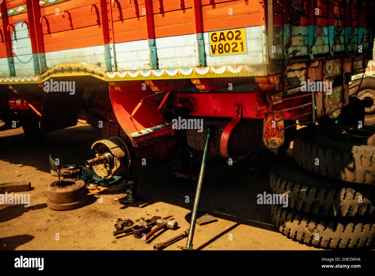 Truck mechanic posing with the lorry he is working on in the open air ...