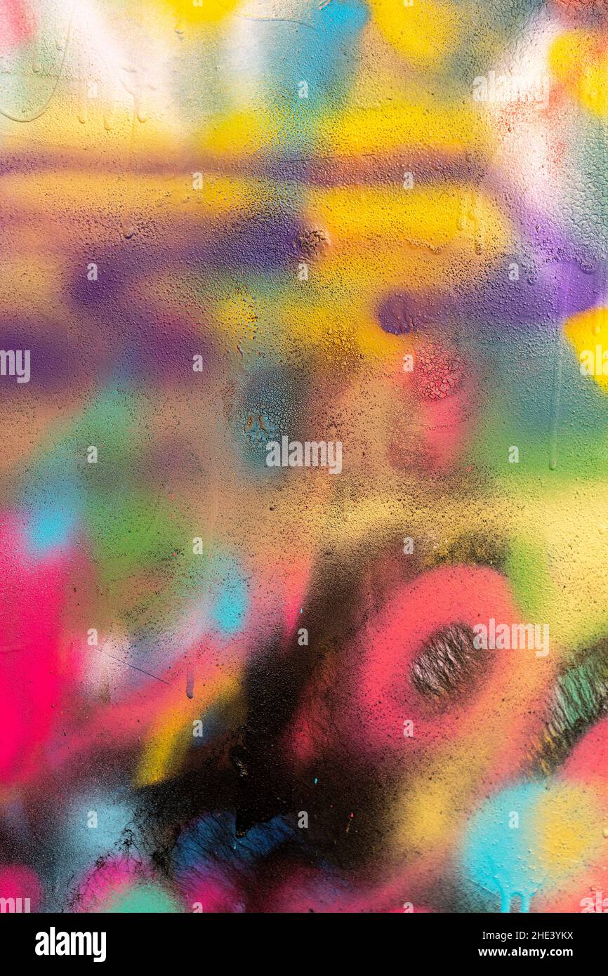 Some colorful and splattered spray paint graffiti over a cracked ...