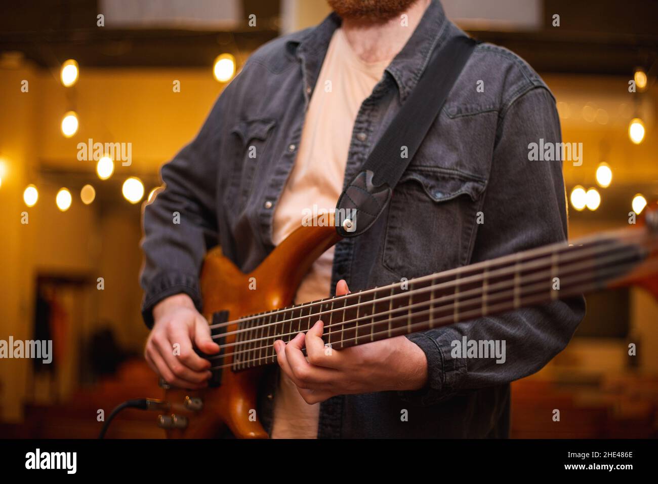 A young guy with a beard plays a bass guitar with five strings Stock ...
