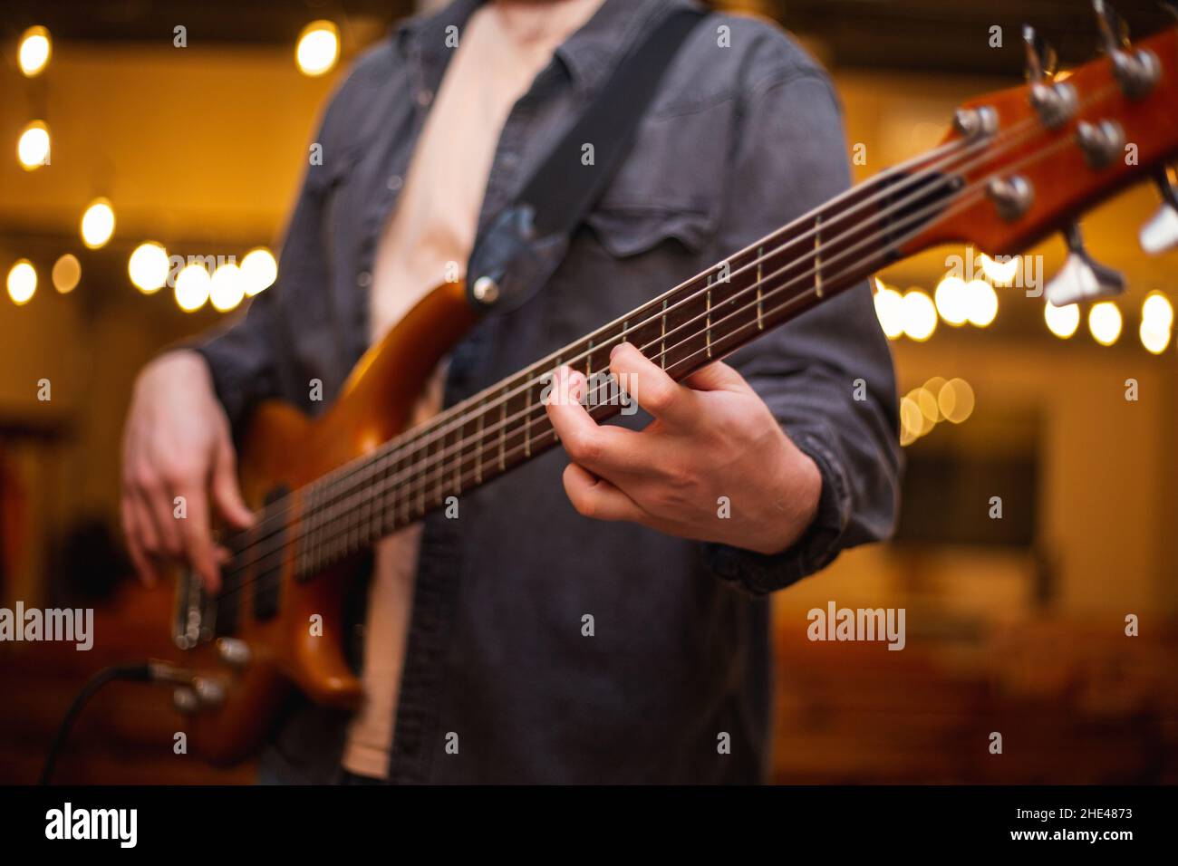 A young guy with a beard plays a bass guitar with five strings Stock ...