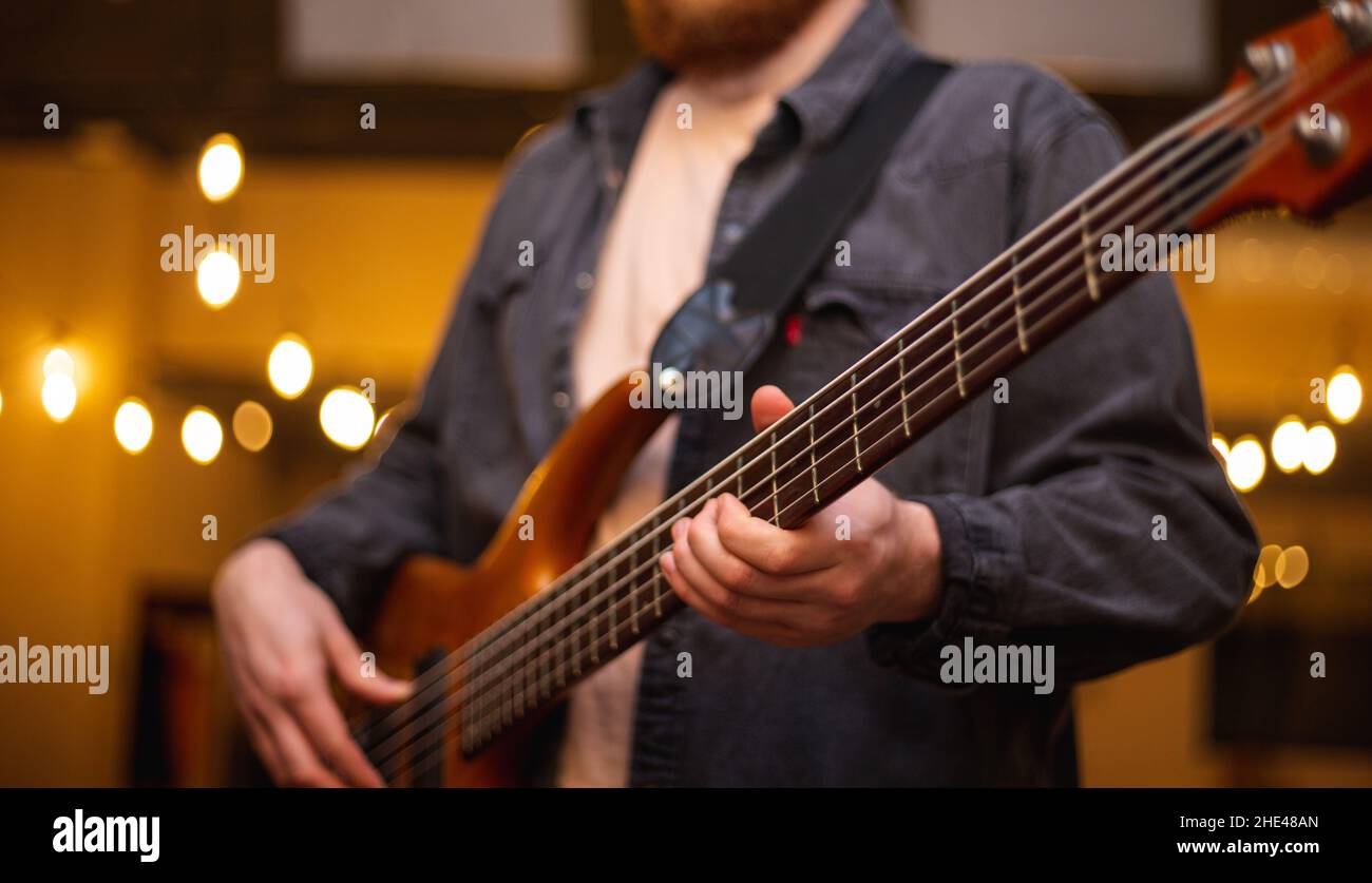 A young guy with a beard plays a bass guitar with five strings Stock ...