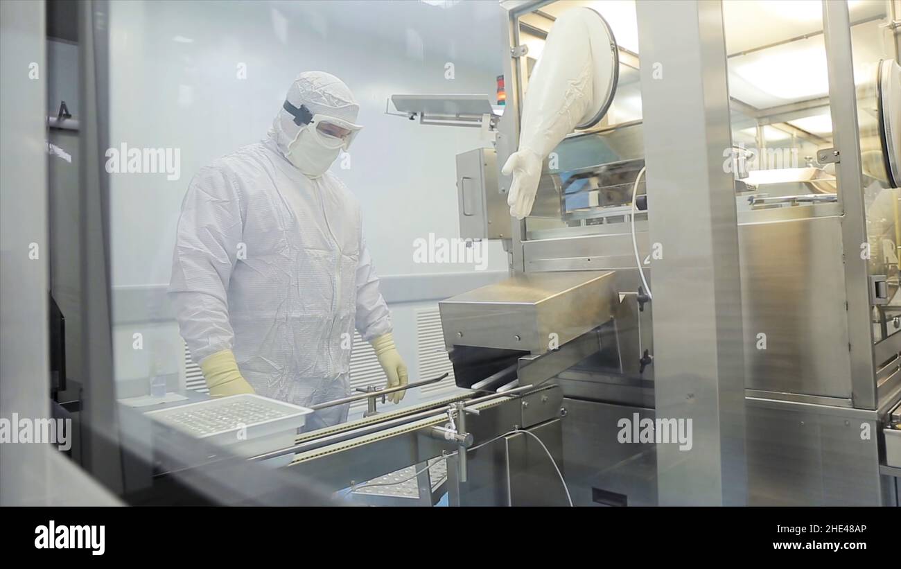 Worker in apron, cap, gloves with tablet checking process at production ...