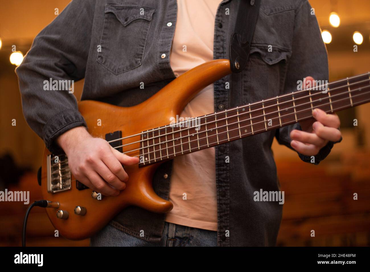 A young guy with a beard plays a bass guitar with five strings Stock ...