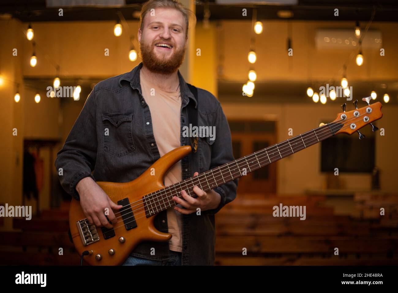 A young guy with a beard plays a bass guitar with five strings Stock ...