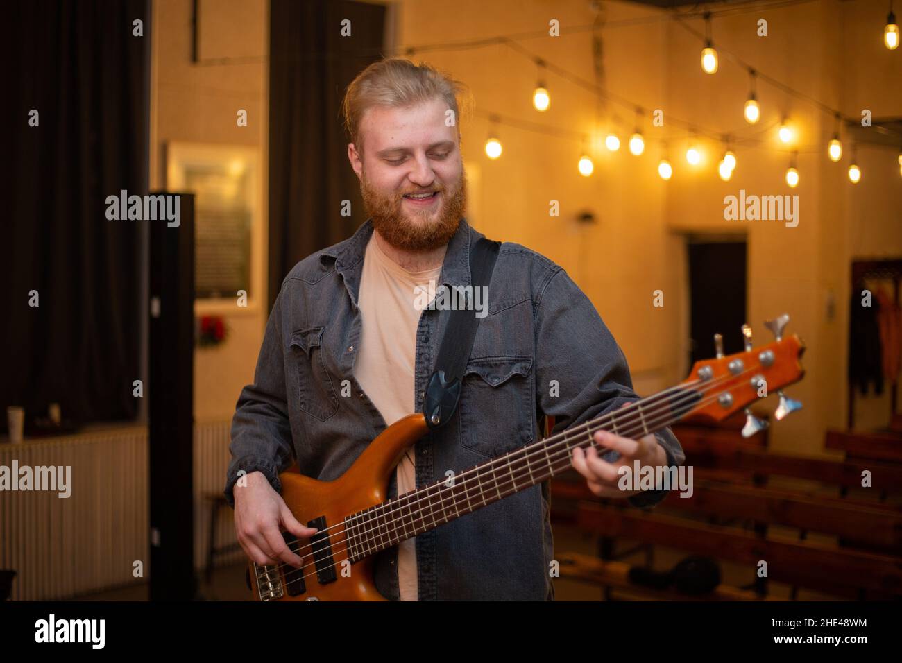 A young guy with a beard plays a bass guitar with five strings Stock ...