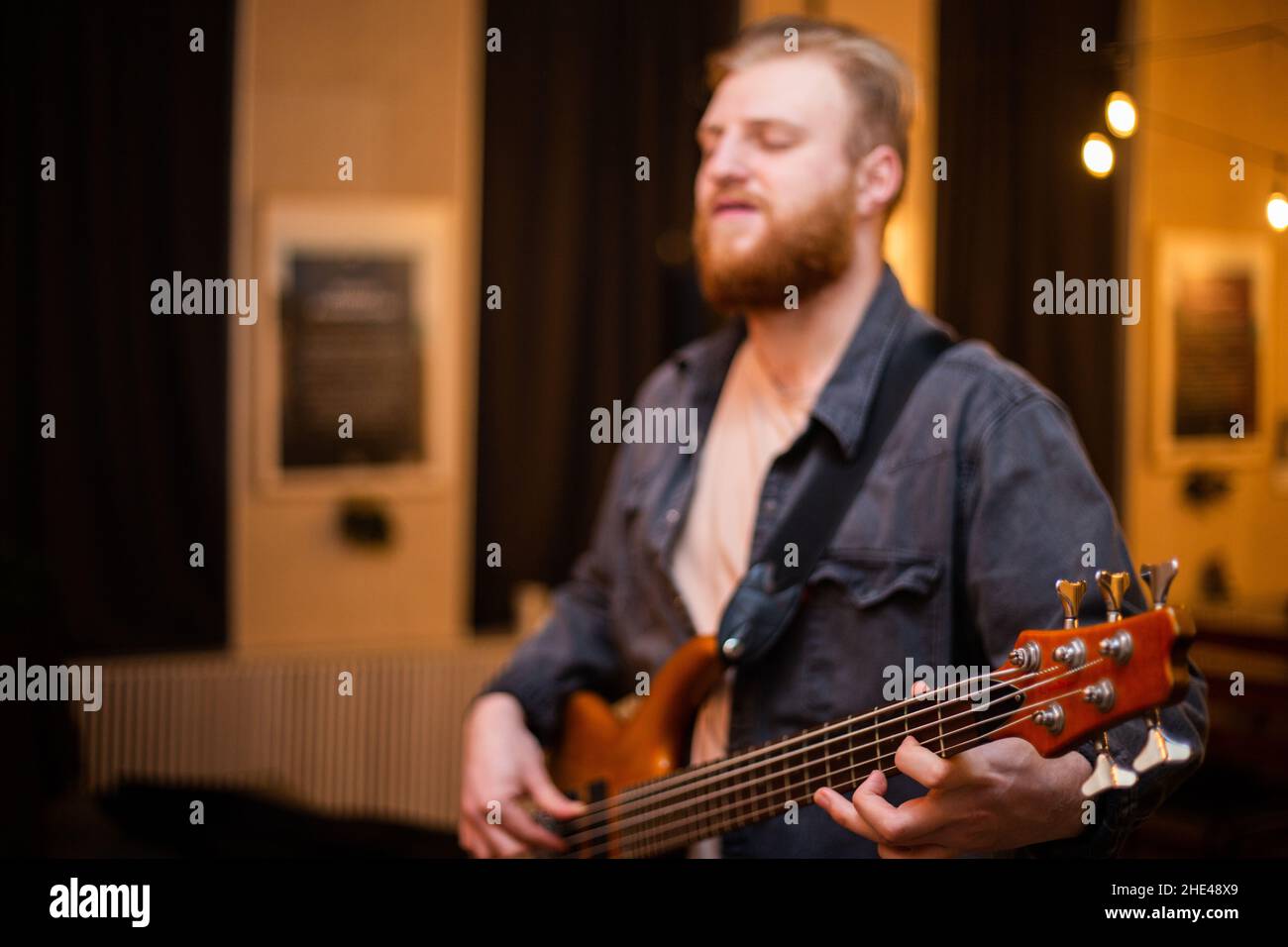 A young guy with a beard plays a bass guitar with five strings Stock ...