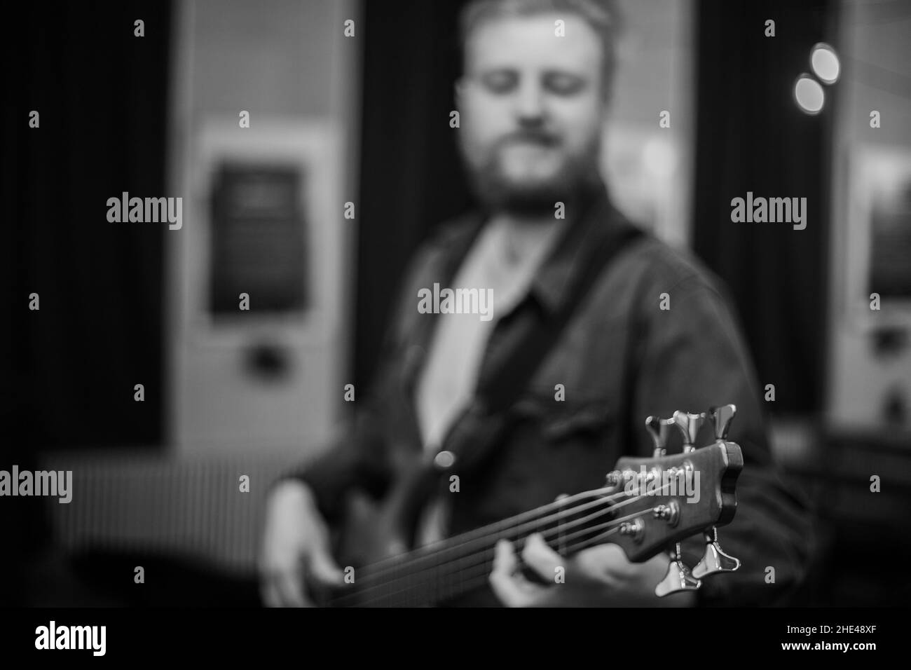 A young guy with a beard plays a bass guitar with five strings Stock ...