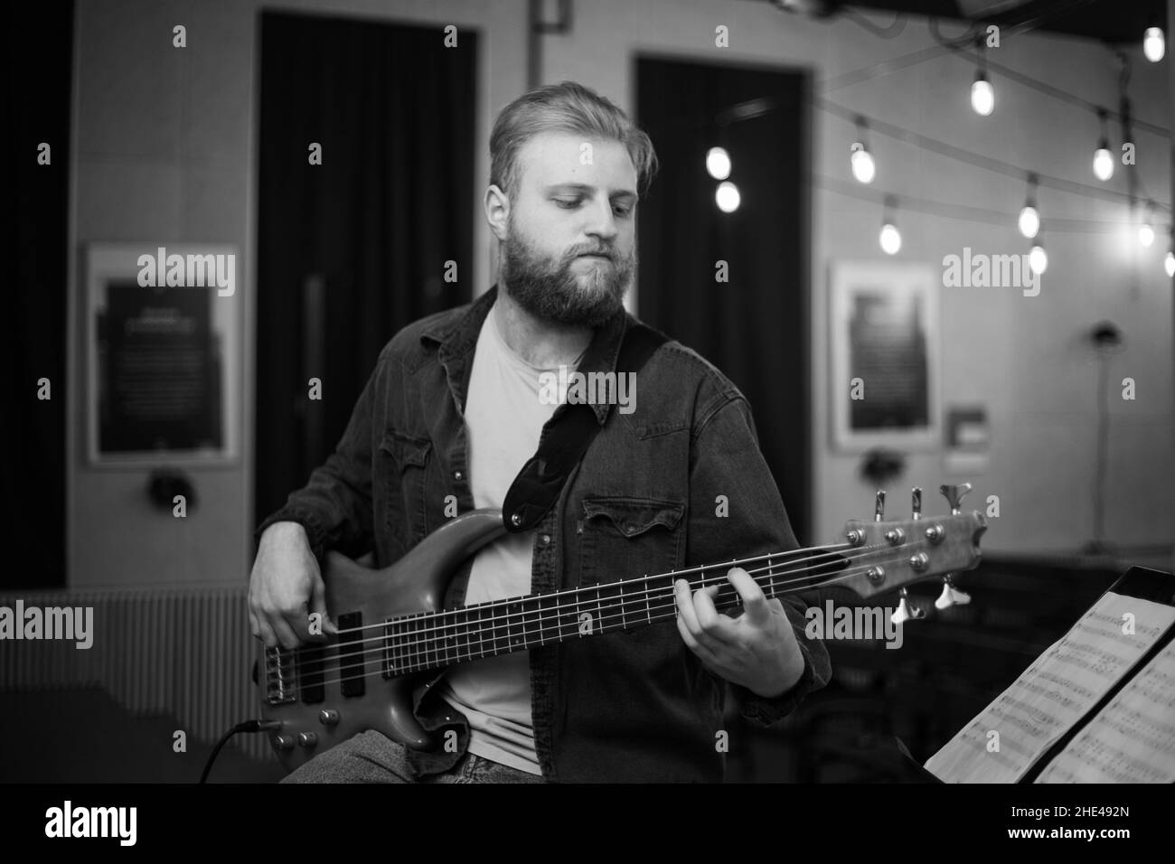 A young guy with a beard plays a bass guitar with five strings Stock ...