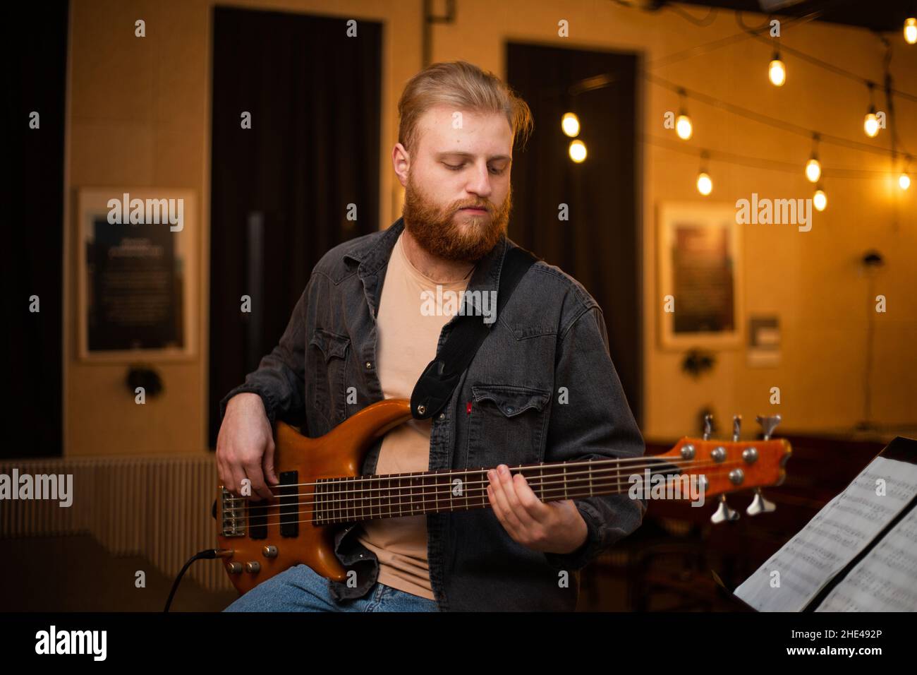 A young guy with a beard plays a bass guitar with five strings Stock ...