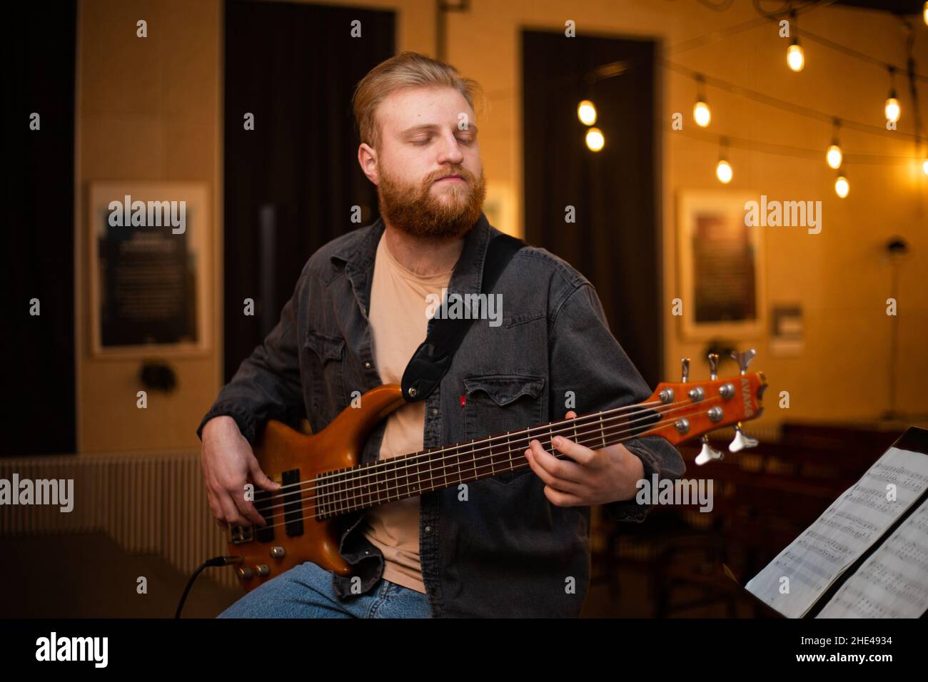 A young guy with a beard plays a bass guitar with five strings Stock ...