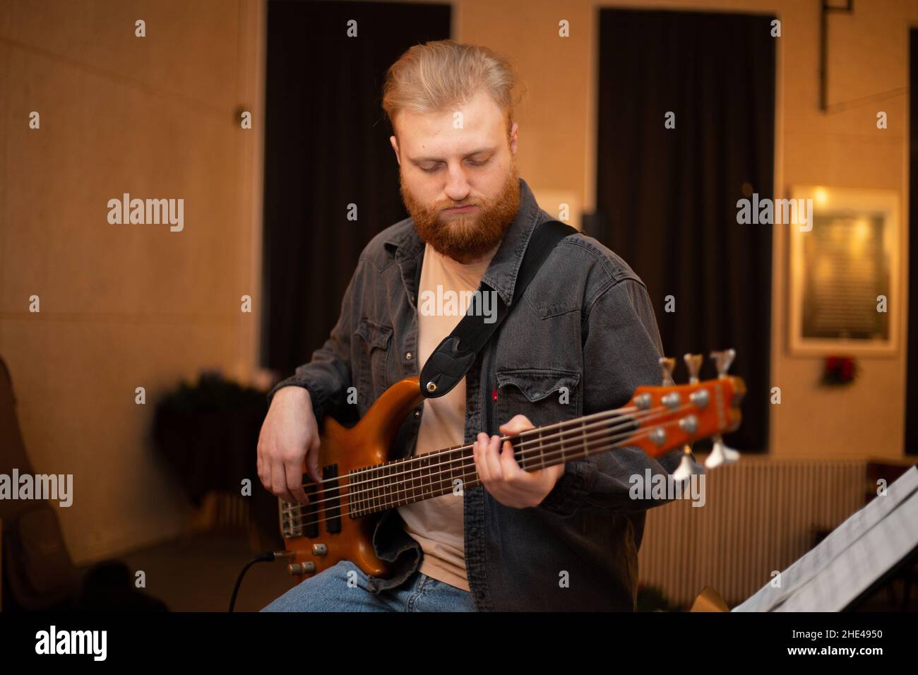 A young guy with a beard plays a bass guitar with five strings Stock ...
