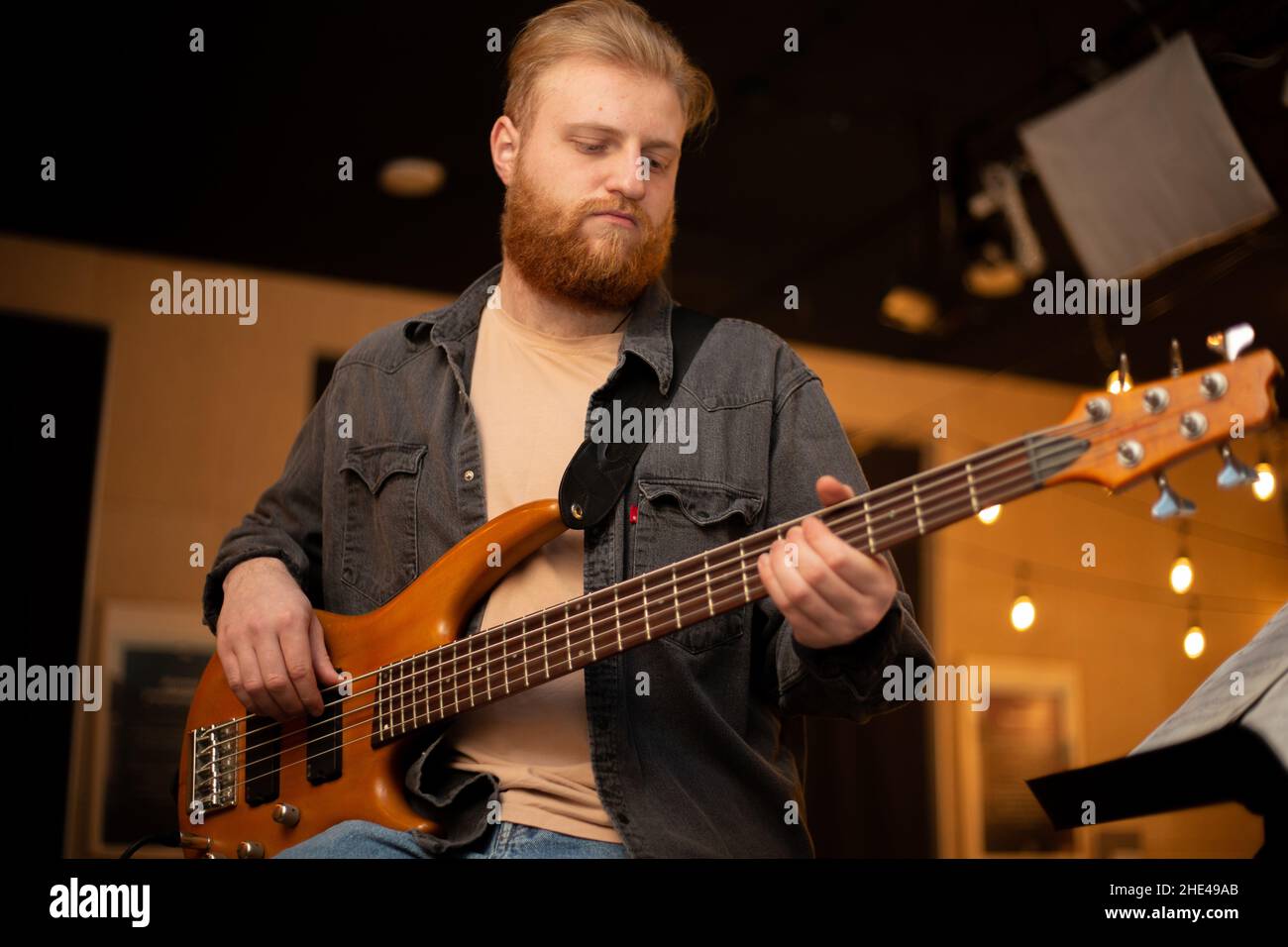 A young guy with a beard plays a bass guitar with five strings Stock ...