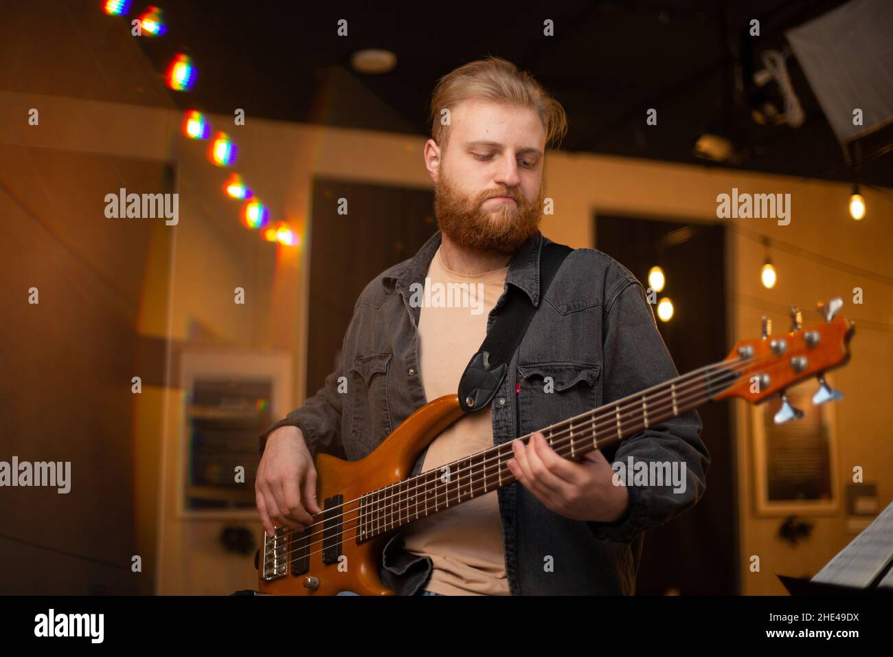 A young guy with a beard plays a bass guitar with five strings Stock ...